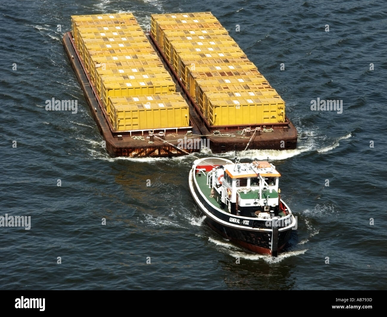 Looking down at tug boat pulling barges loaded with containers full of ...