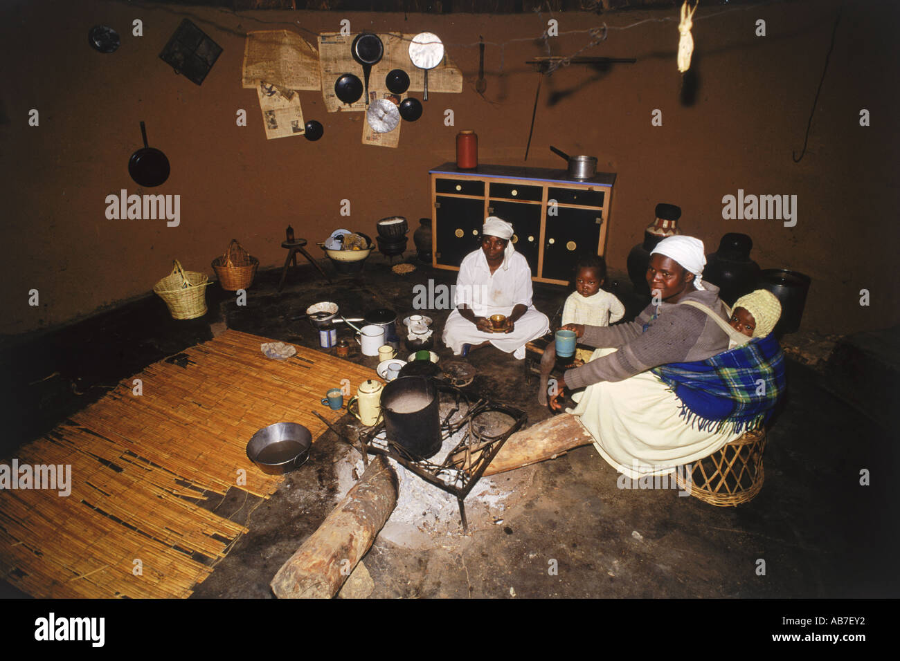 Mothers with their children cooking food in basic African village hut ...