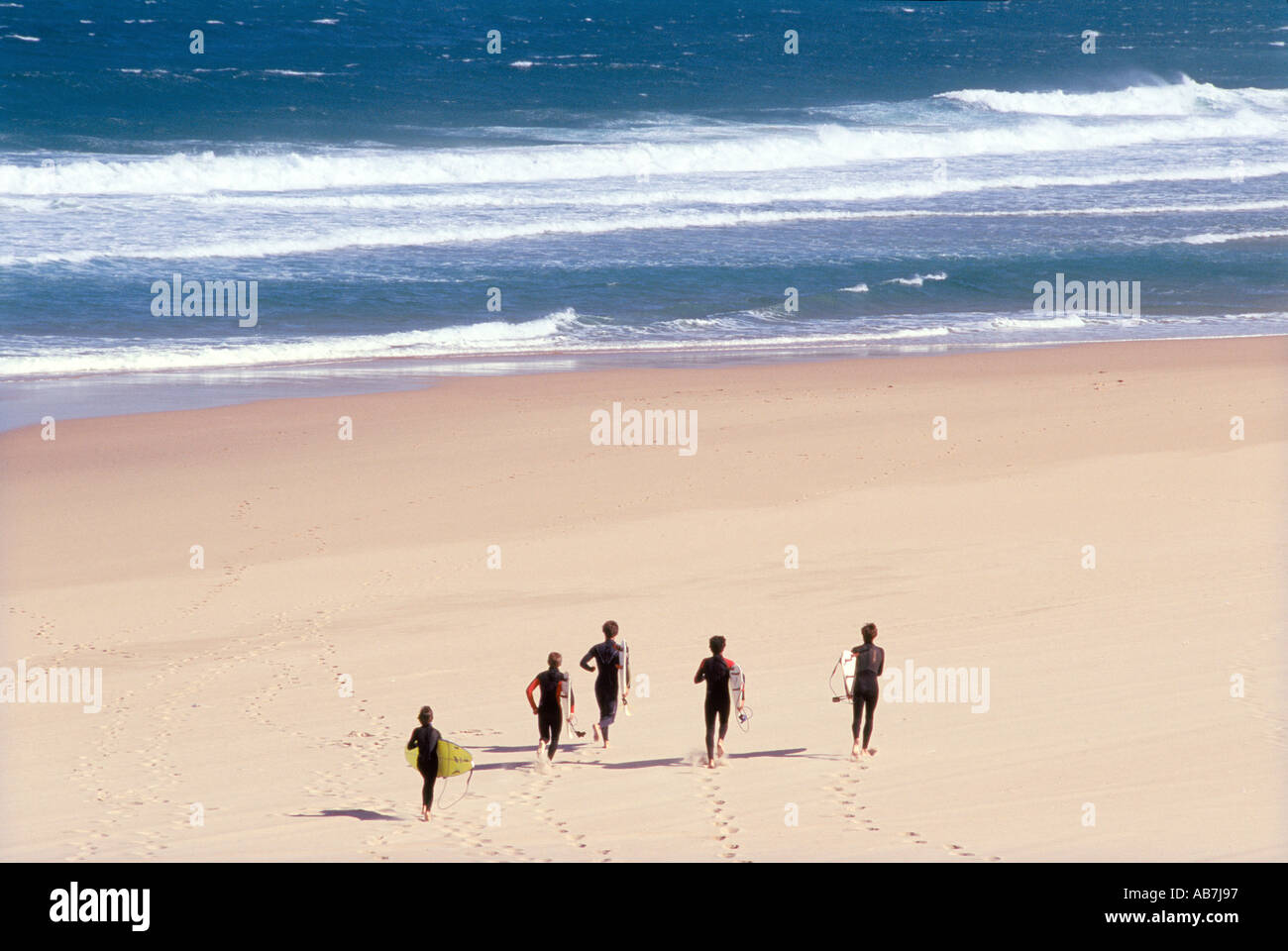 Surfers run across the sand at Guincho the famous surfing beach near ...
