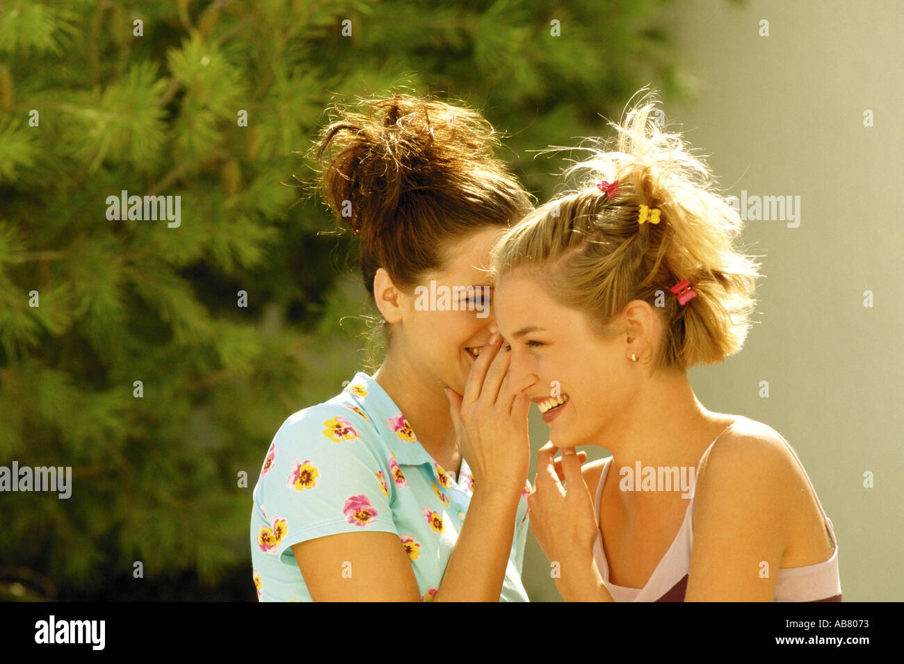 Two laughing young women whispering hi-res stock photography and images ...