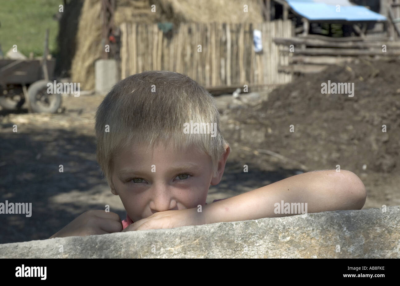 blond boy watching over a wall, Romania Stock Photo - Alamy