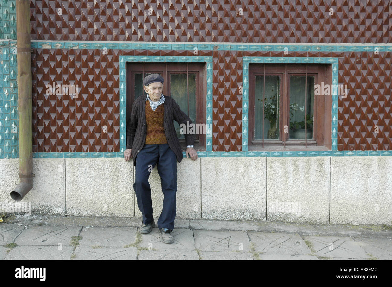 old man leaning against house wall, Romania Stock Photo - Alamy