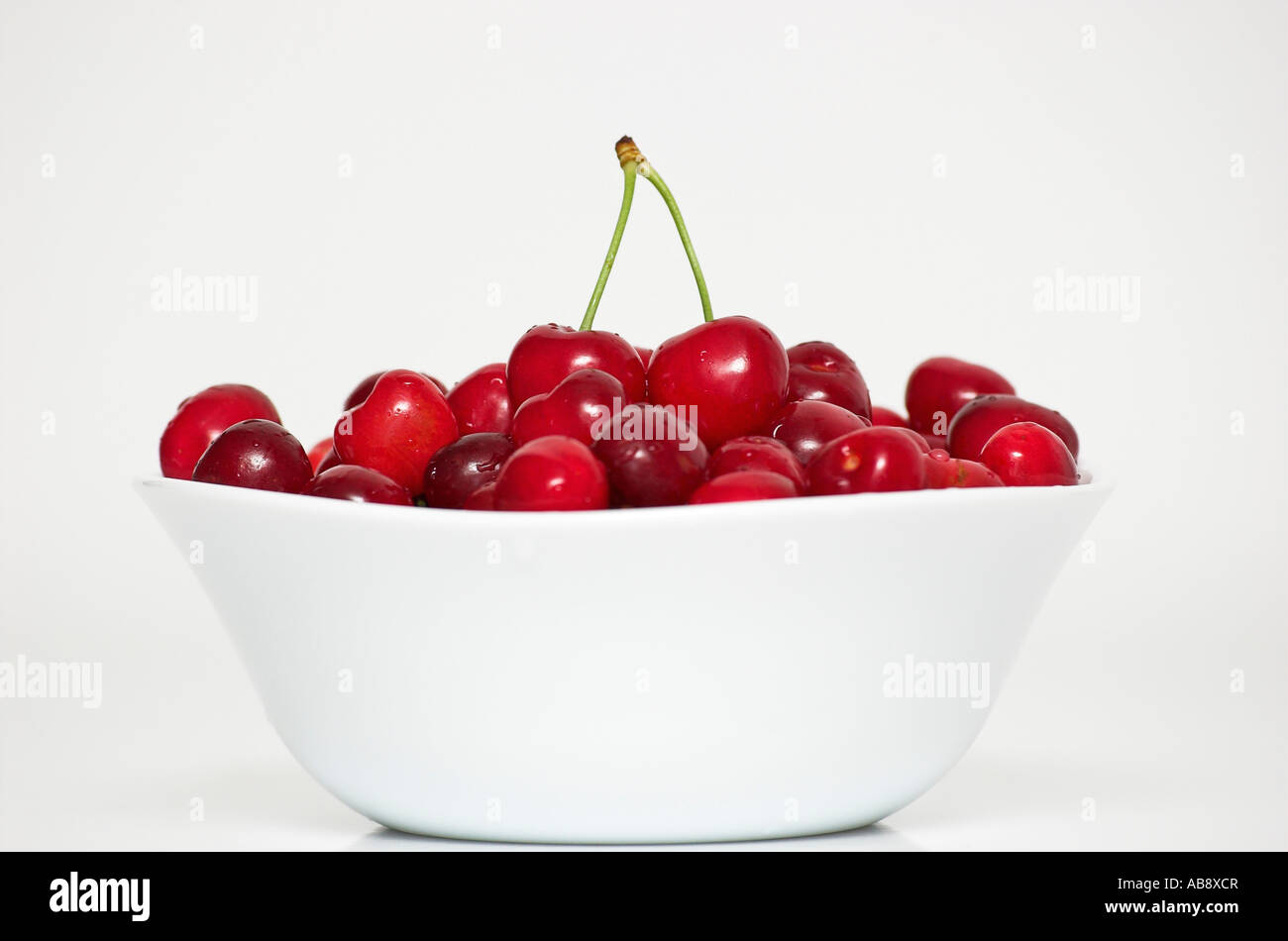 Fresh cherries in white bowl against white background Stock Photo - Alamy