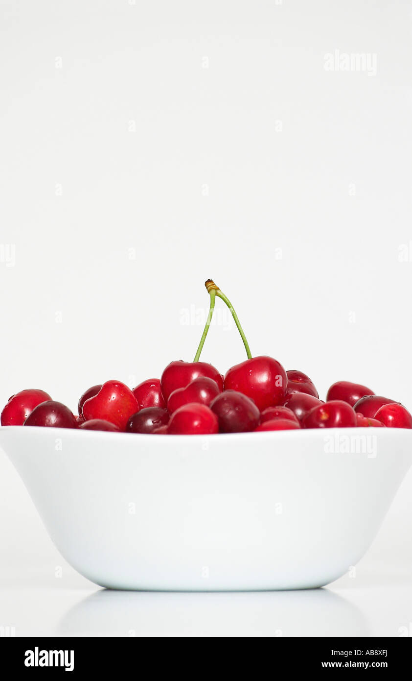 Fresh cherries in white bowl against white background Stock Photo - Alamy