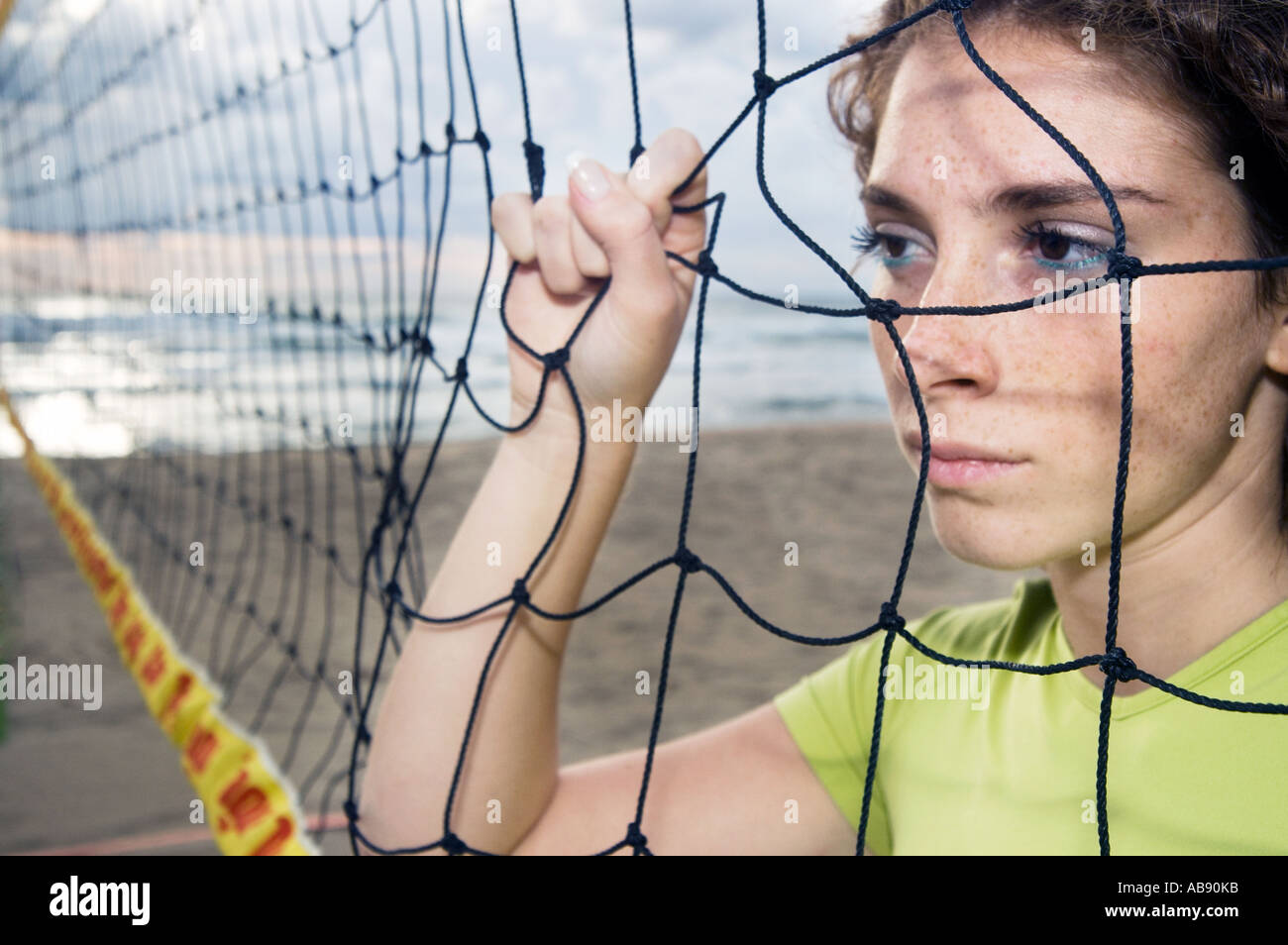 Young woman standing on the beach holding volleyball net Stock Photo ...