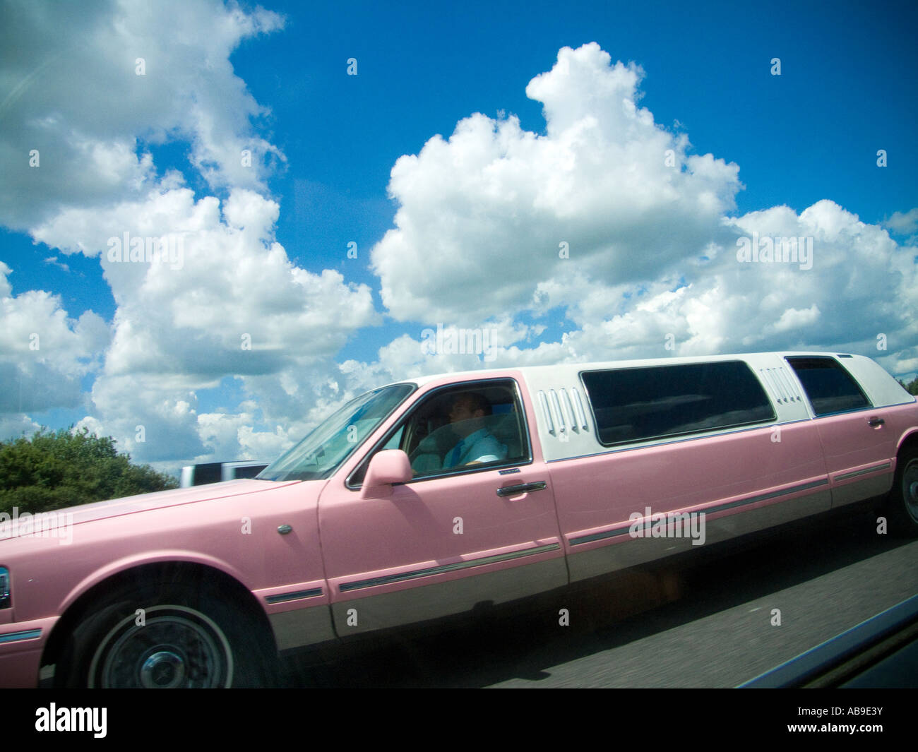 Pink limosine overtaking on a motorway, blue sky and dramatic clouds ...