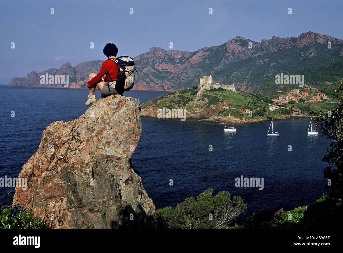 wanderer sitting on a rock looking out to Gulf of Porto and Martello ...