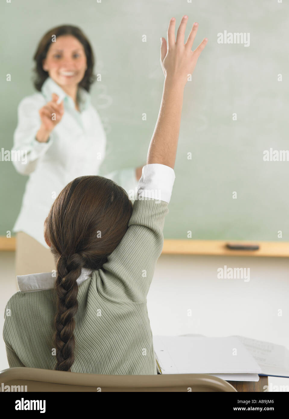 Young girl raising her hand in class Stock Photo - Alamy