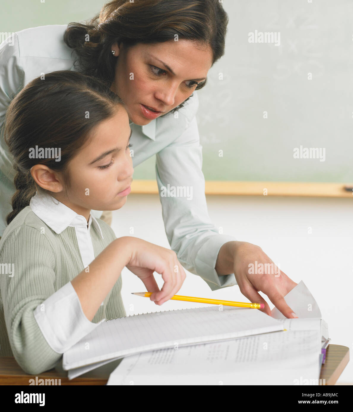 Teacher helping young student with work Stock Photo - Alamy