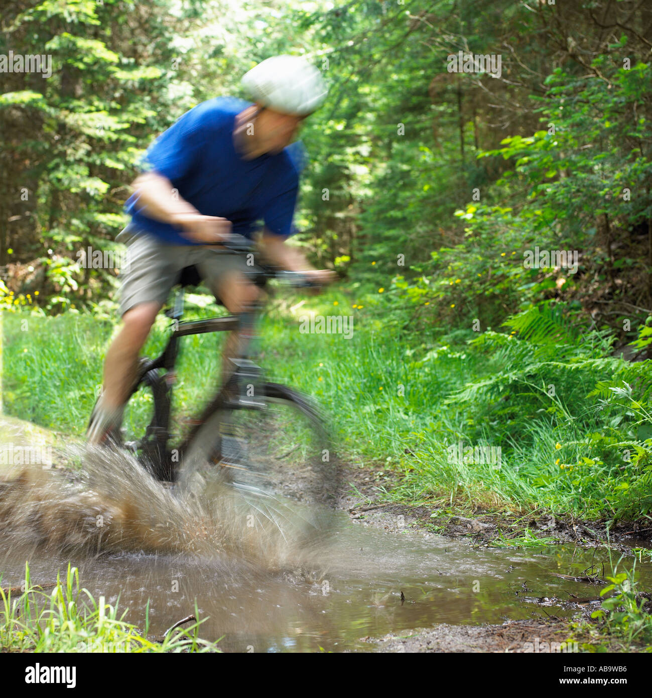 Male Cyclist riding on a muddy trail splashing water Stock Photo - Alamy