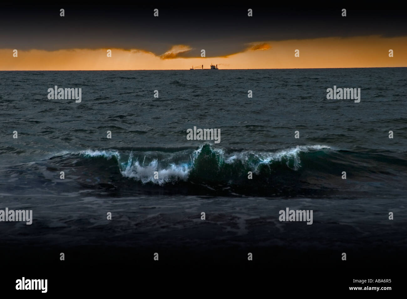 a strong wave and a ship during sunset Stock Photo - Alamy