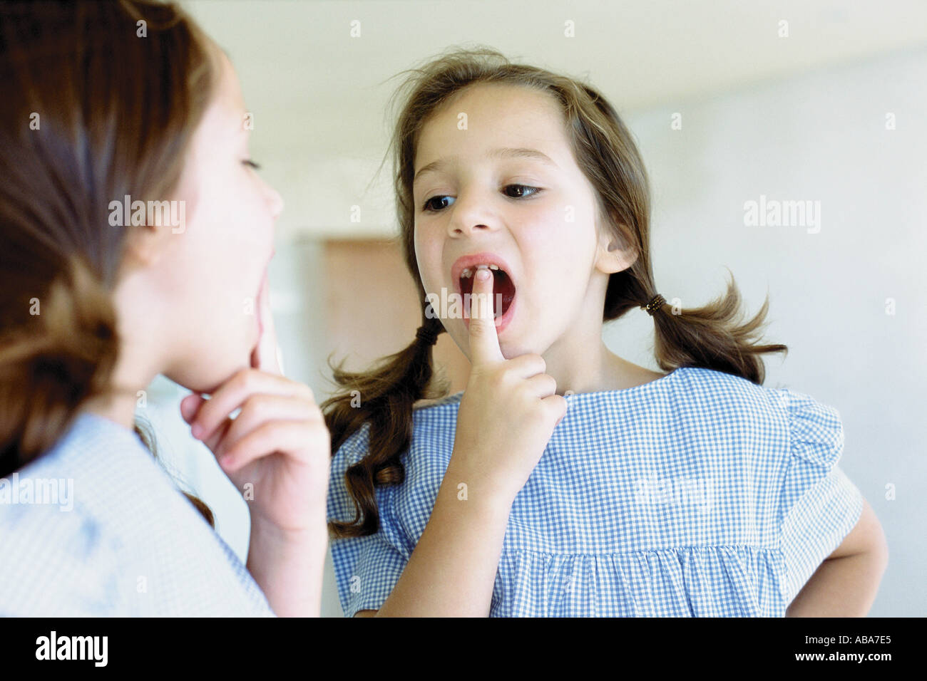 Girl looking at her missing tooth in the mirror Stock Photo - Alamy