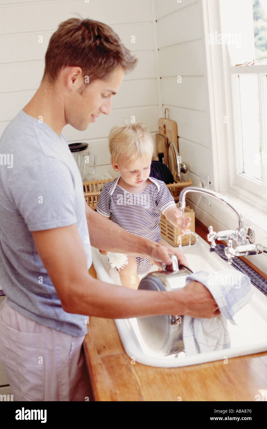 Father washing up and child playing with water Stock Photo - Alamy