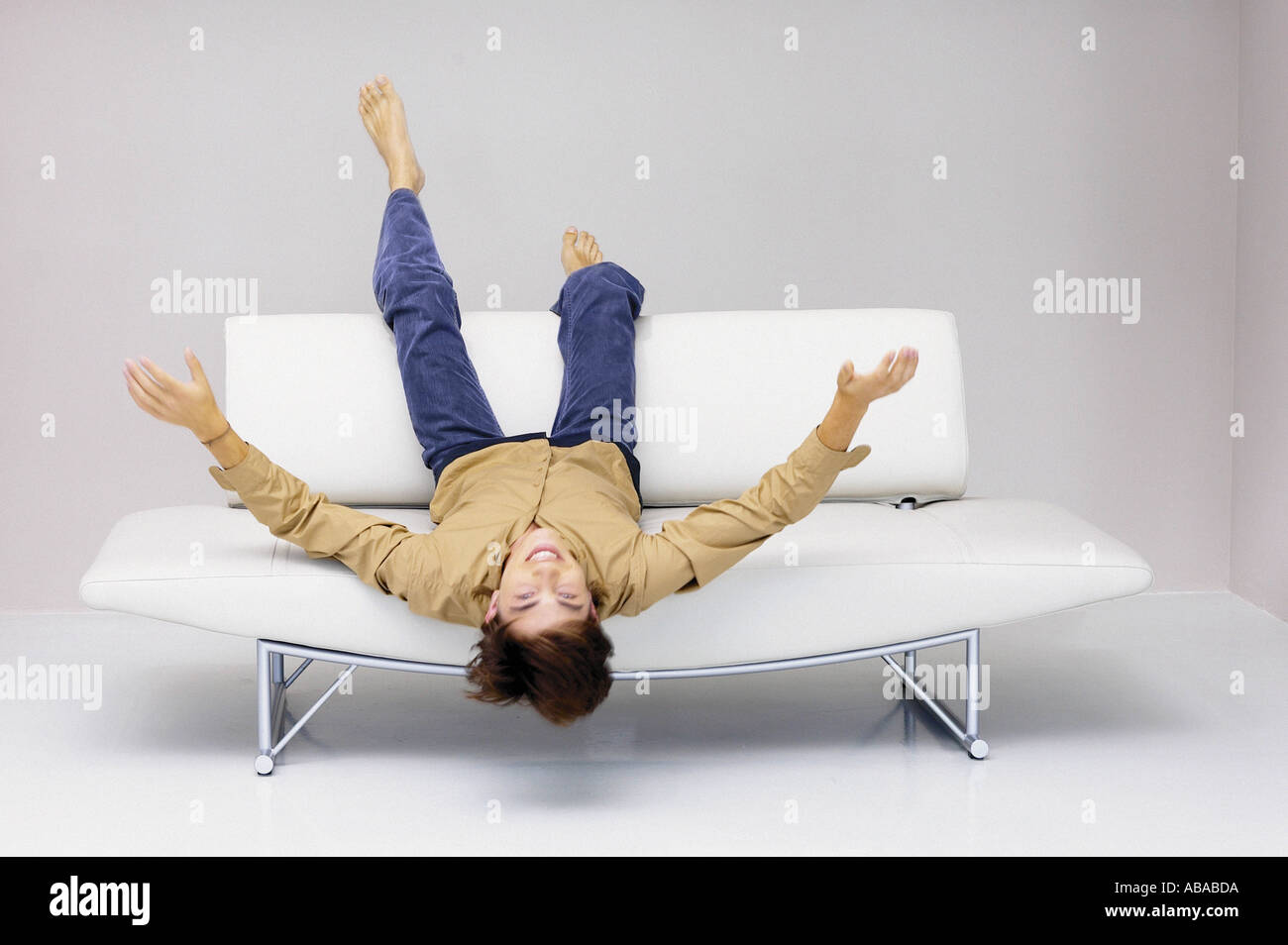 Man reclining on modern sofa Stock Photo - Alamy