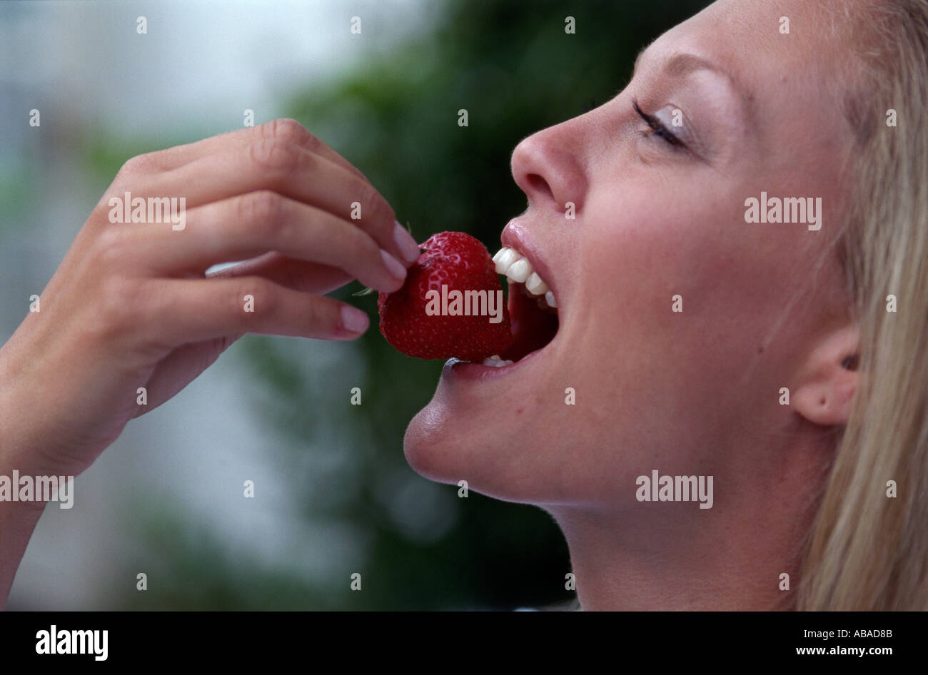 Girl eating strawberry Stock Photo - Alamy