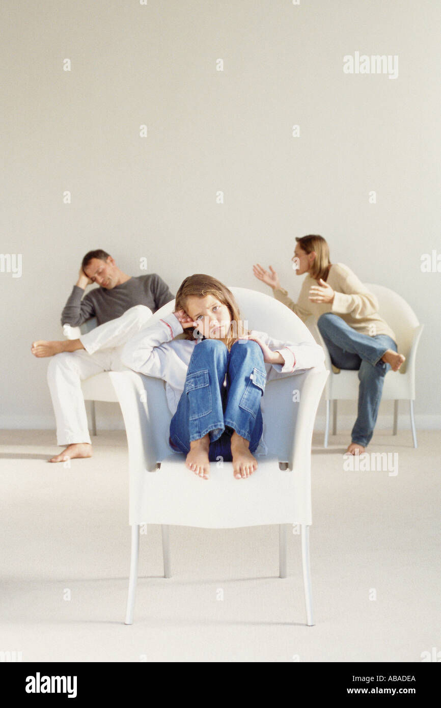 Girl in chair with parents arguing Stock Photo - Alamy