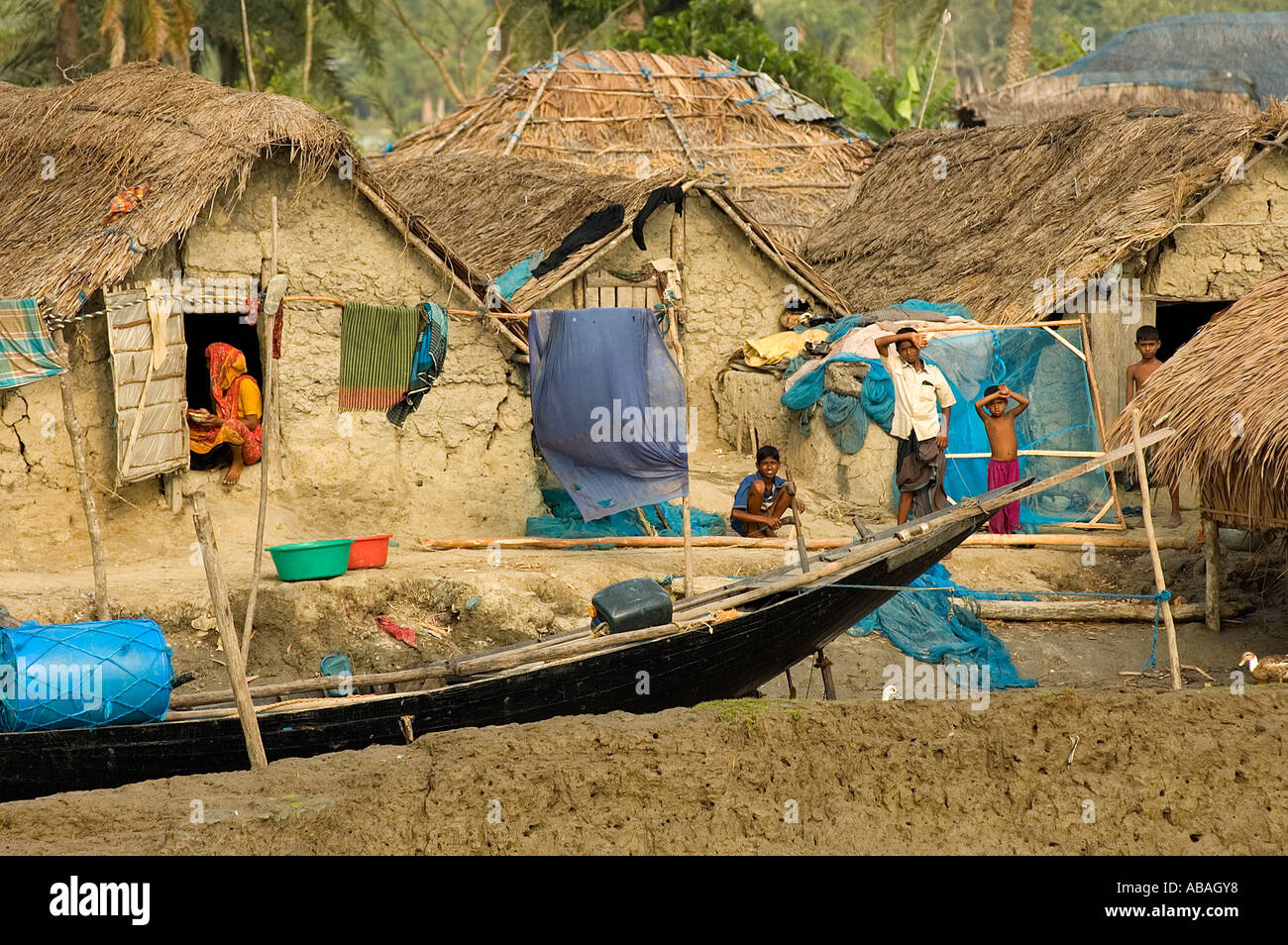 Thatched roof mud houses along river bank in in Passur River Chandpai ...
