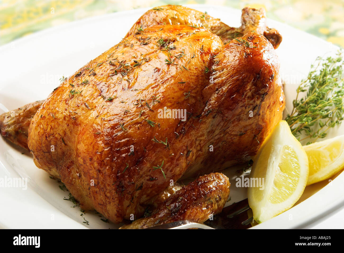 Herb encrusted roasted roast golden brown chicken on a white plate with ...