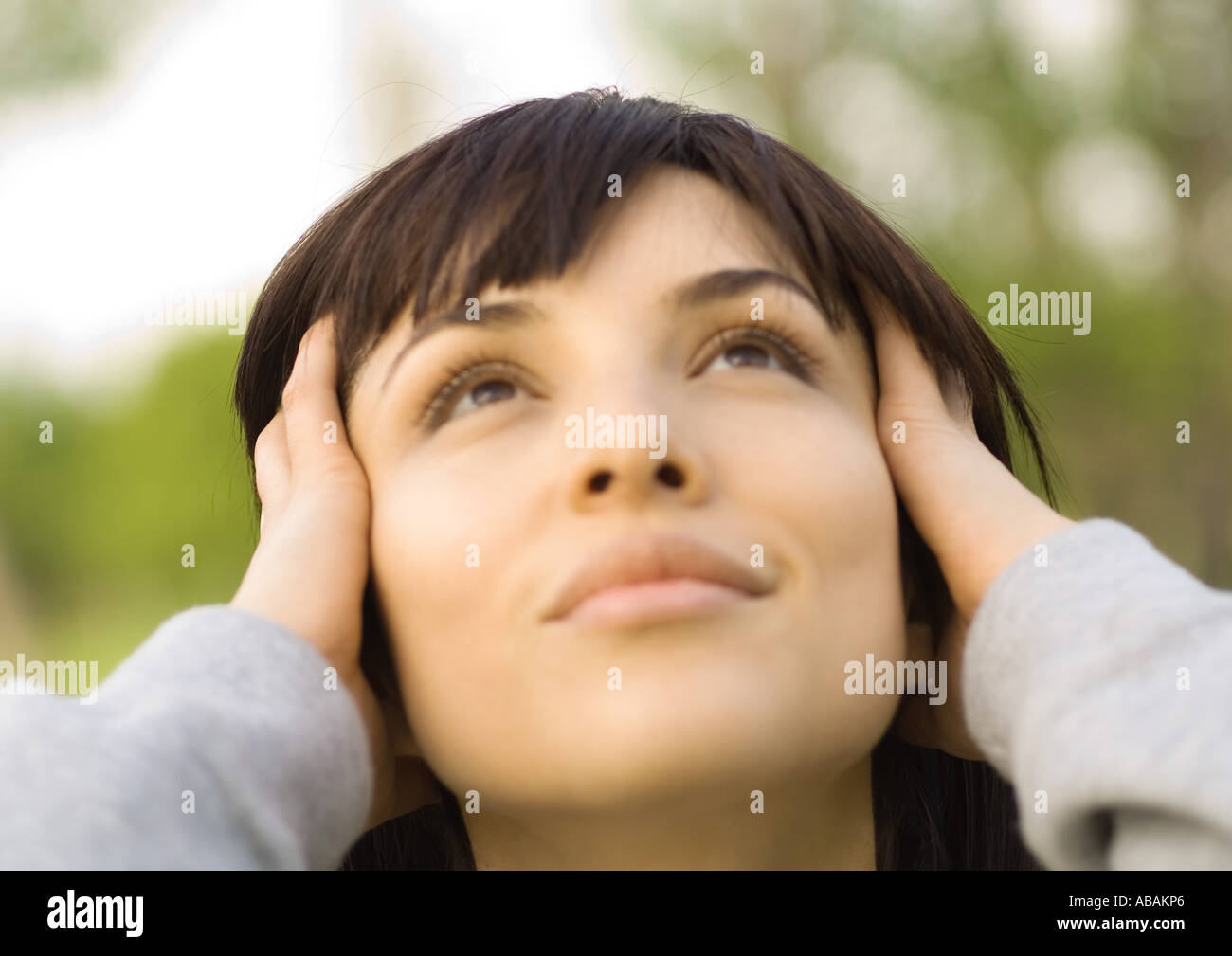 Woman with hands in hair, looking up Stock Photo - Alamy