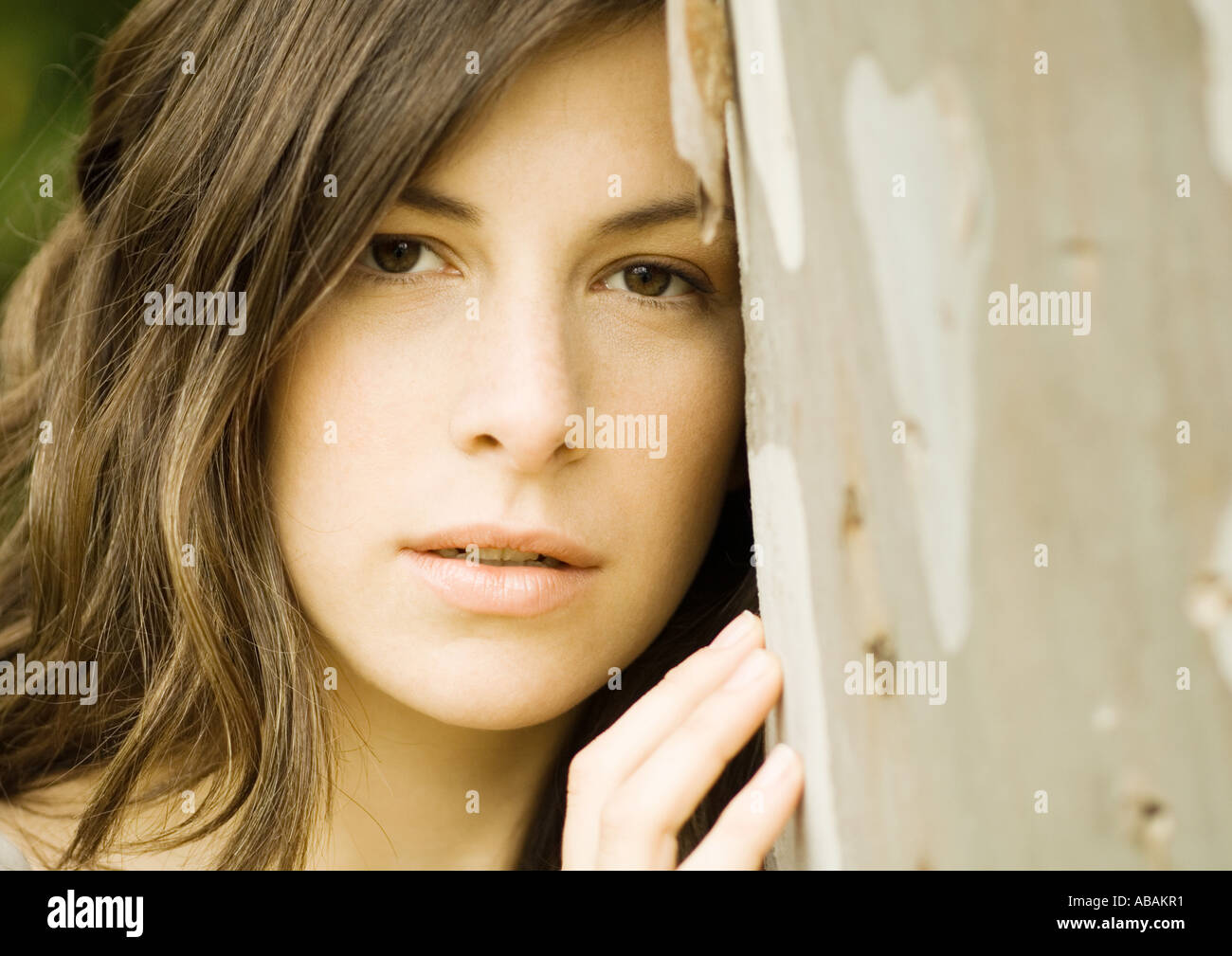 Woman leaning head against tree trunk Stock Photo - Alamy