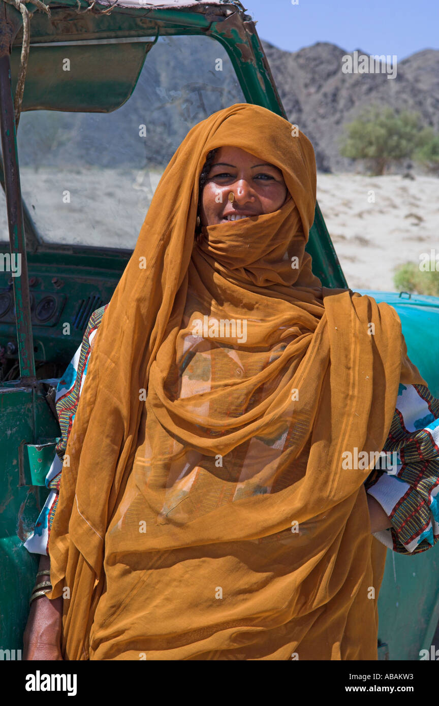 Three quarter portrait Ababda tribeswoman standing by 4x4 land rover in ...