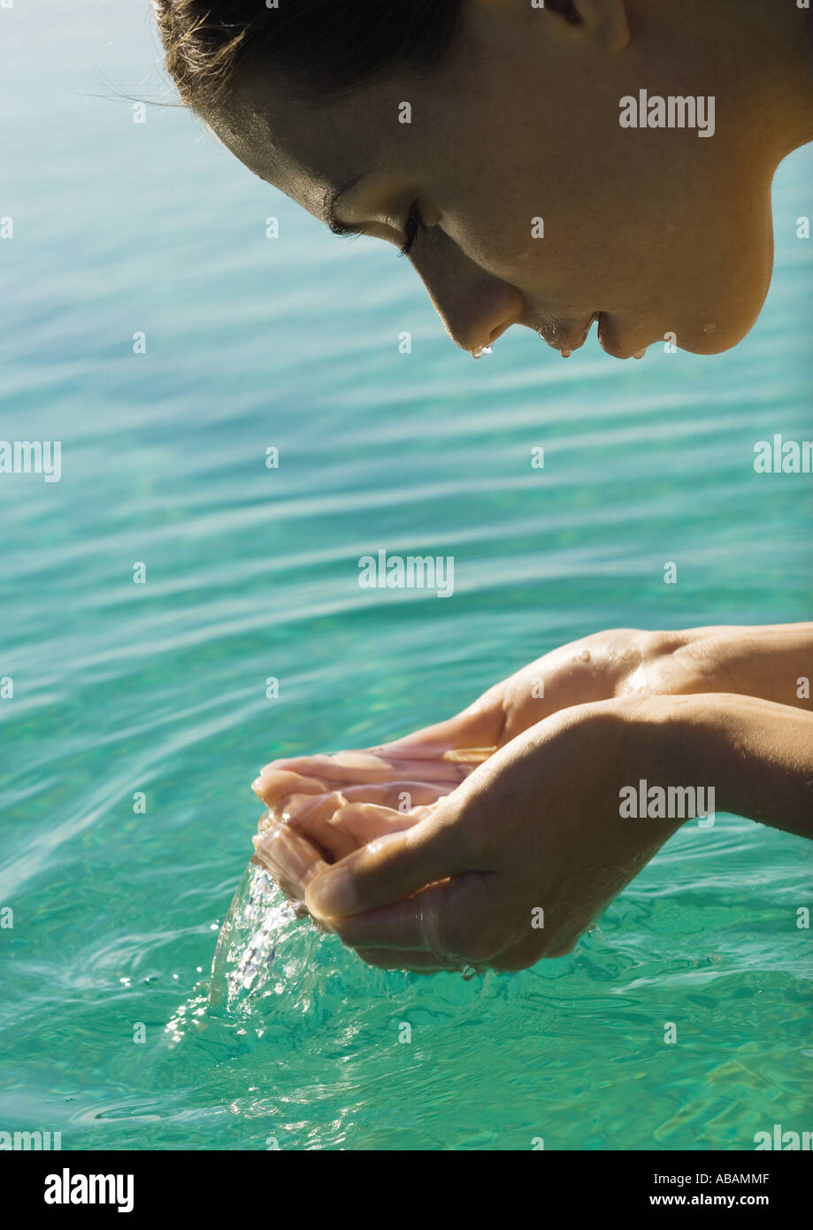 Woman leaning face over water, cupping water in hands Stock Photo - Alamy