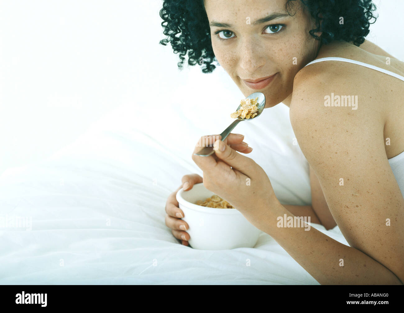 Woman lying on stomach in bed, eating cereal Stock Photo - Alamy