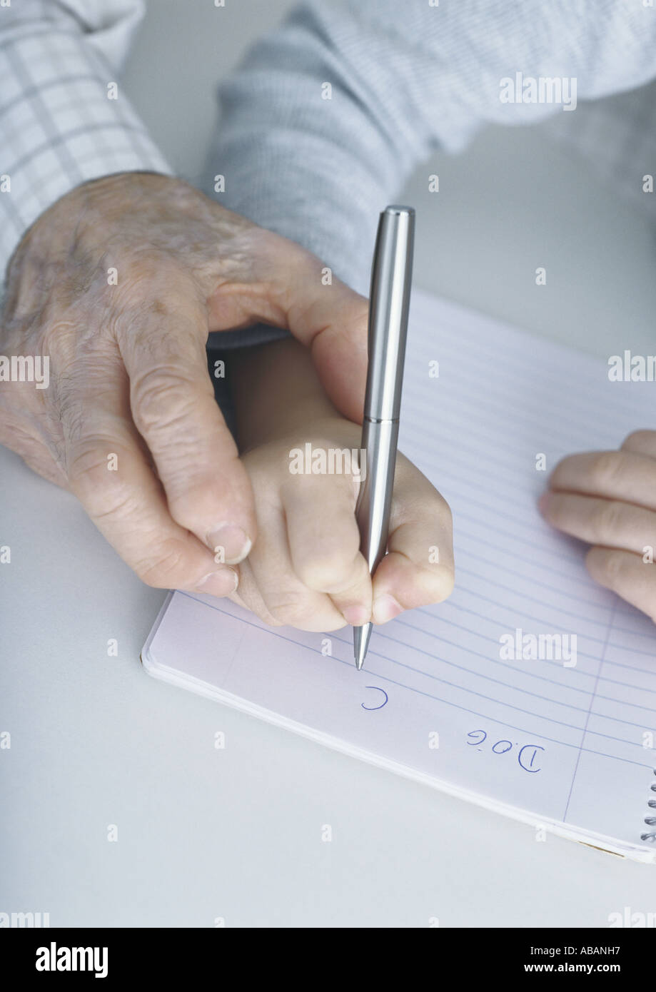 Elderly person's hand guiding child's, writing in notebook Stock Photo ...