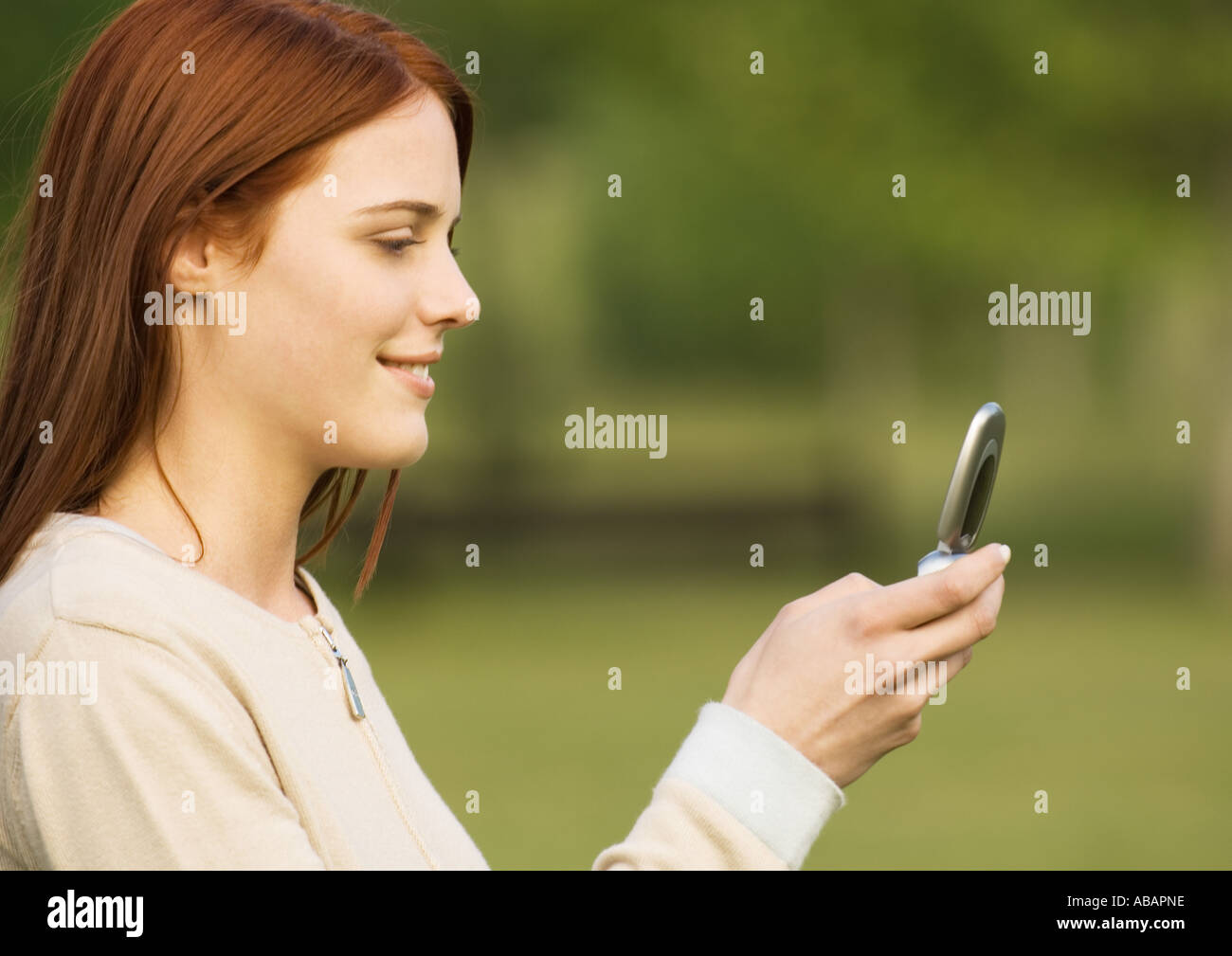 Young woman looking at cell phone, side view Stock Photo - Alamy