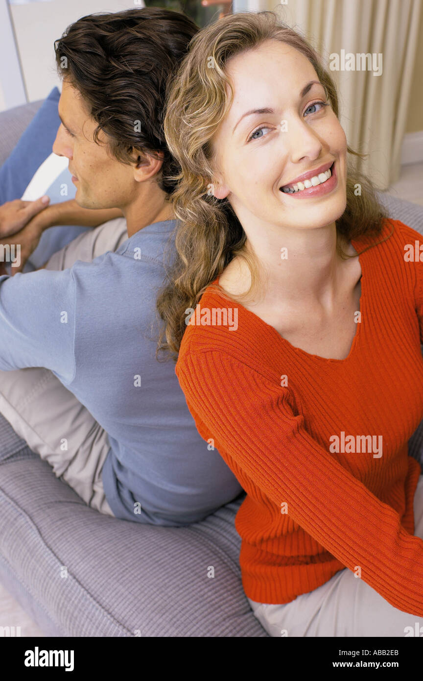 Young couple sitting back to back Stock Photo - Alamy