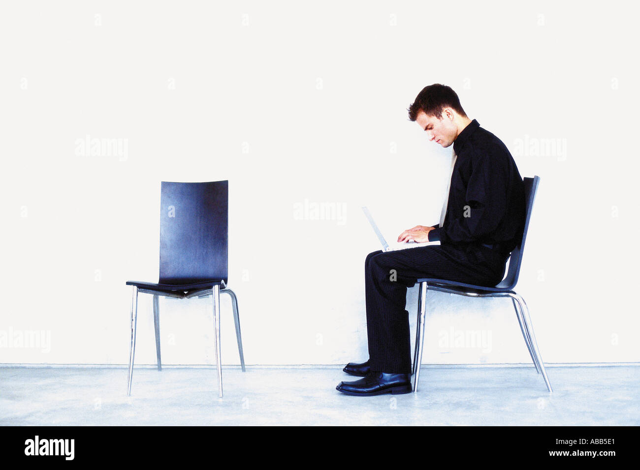 Man sitting on chair with laptop computer Stock Photo - Alamy