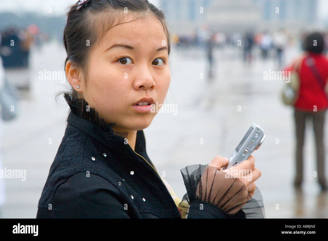 Young Chinese woman using cellphone to dial or text Tiananmen Square ...
