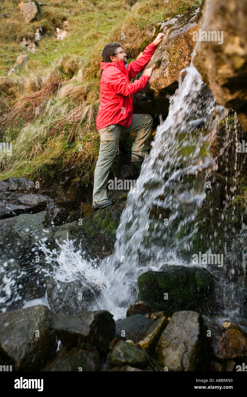 a man scrambling on rocks on a waterfall in Helvelyyn Ghyll, Helvellyn ...