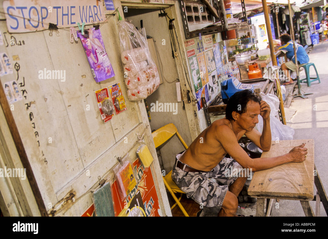 Man sitting outside a shop in Thailand Stock Photo - Alamy