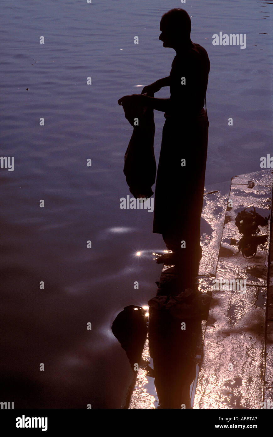 Indian Man washing clothes at banks of holy river ganges in Banaras ...