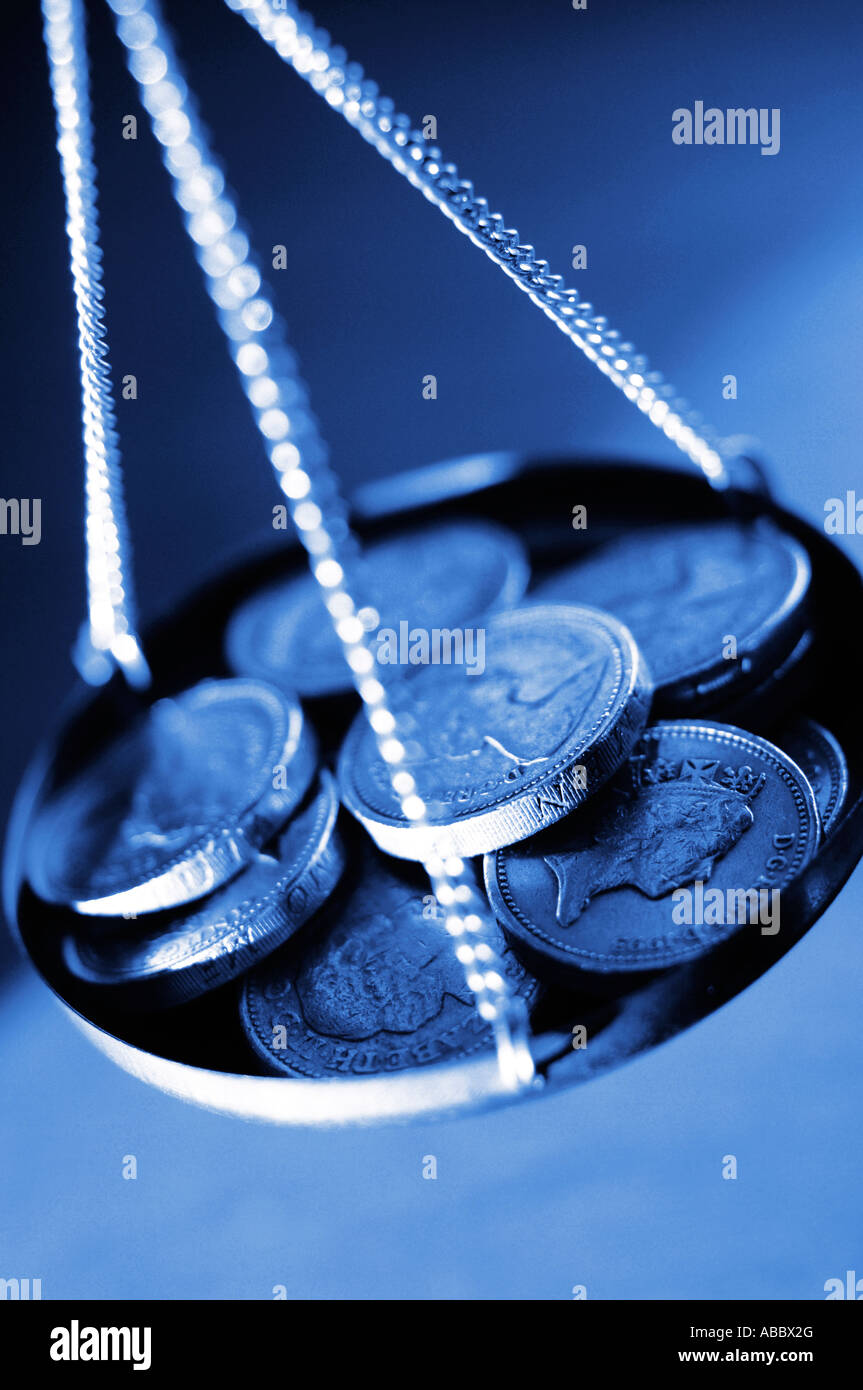 Pound coins in pan of weighing scales Stock Photo - Alamy