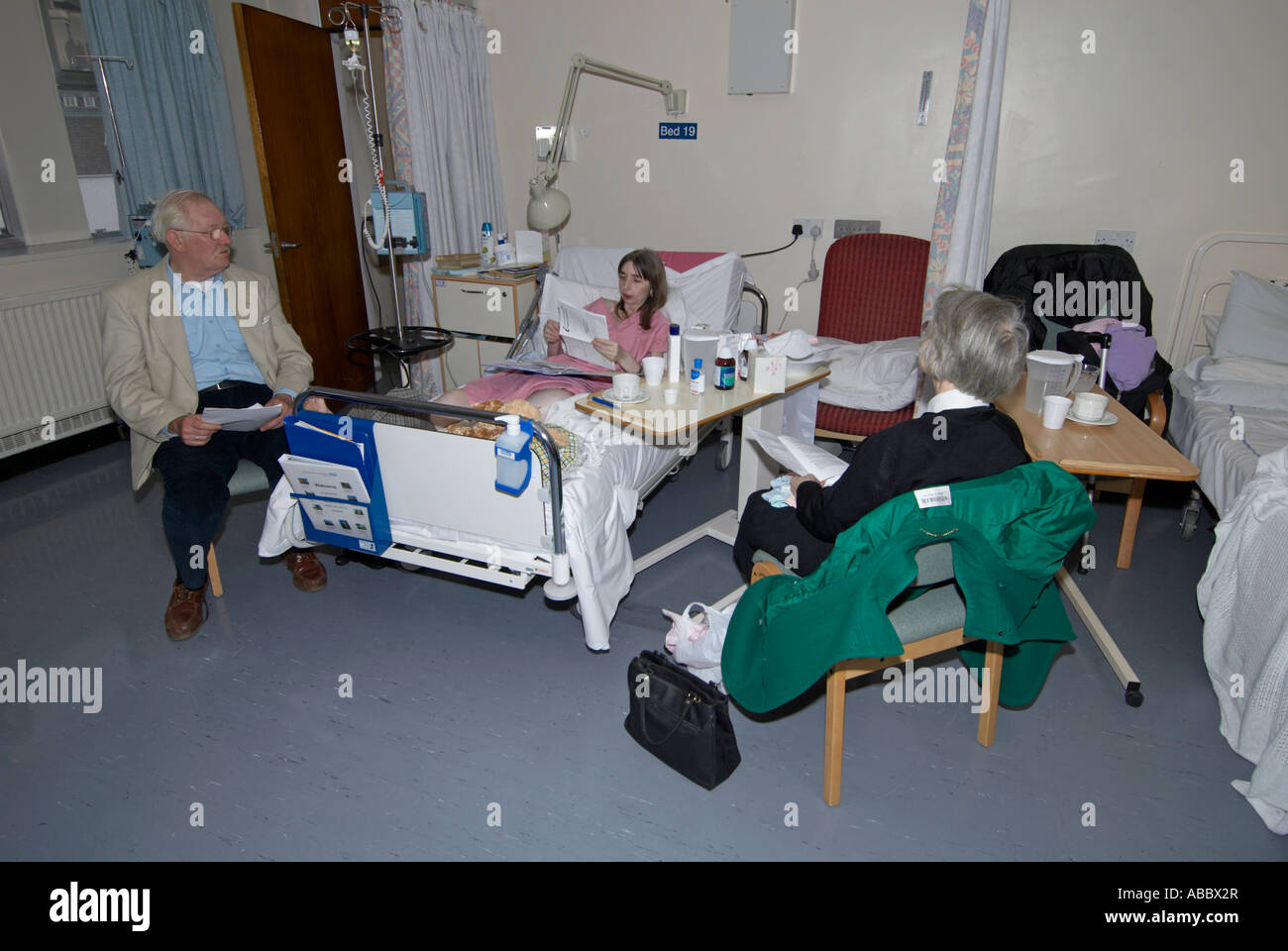 Patient in cancer ward being visited by her parents and reading the ...