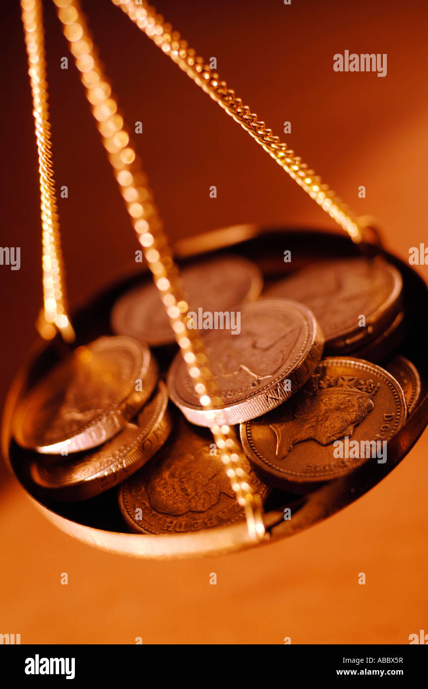 Pound coins in pan of weighing scales Stock Photo - Alamy