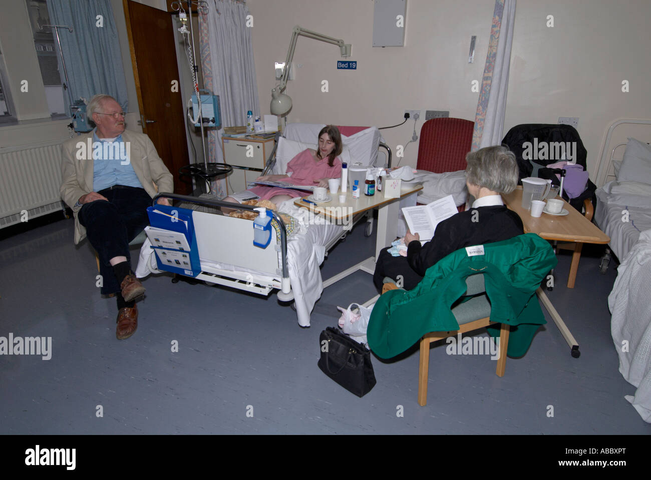 Patient in cancer ward being visited by her parent and reading the ...