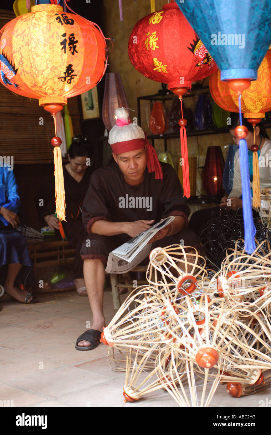 A man reads a newspaper while surrounded by traditional lanterns in Hoi ...