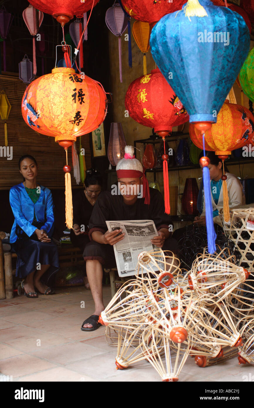 A man reads a newspaper while surrounded by traditional lanterns in Hoi ...