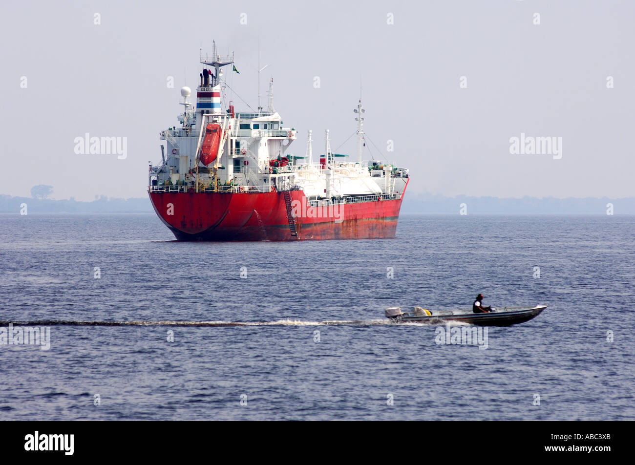 Merchant ship and motorboat come across on the Rio Negro river Brazil ...