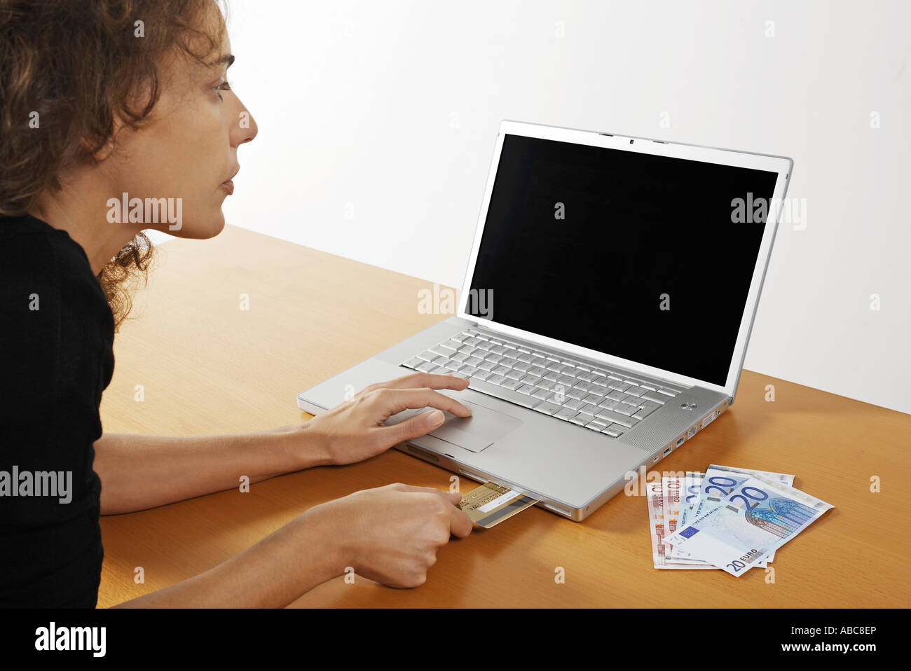 women puting credit card inside the the cd rom opening of a laptop ...