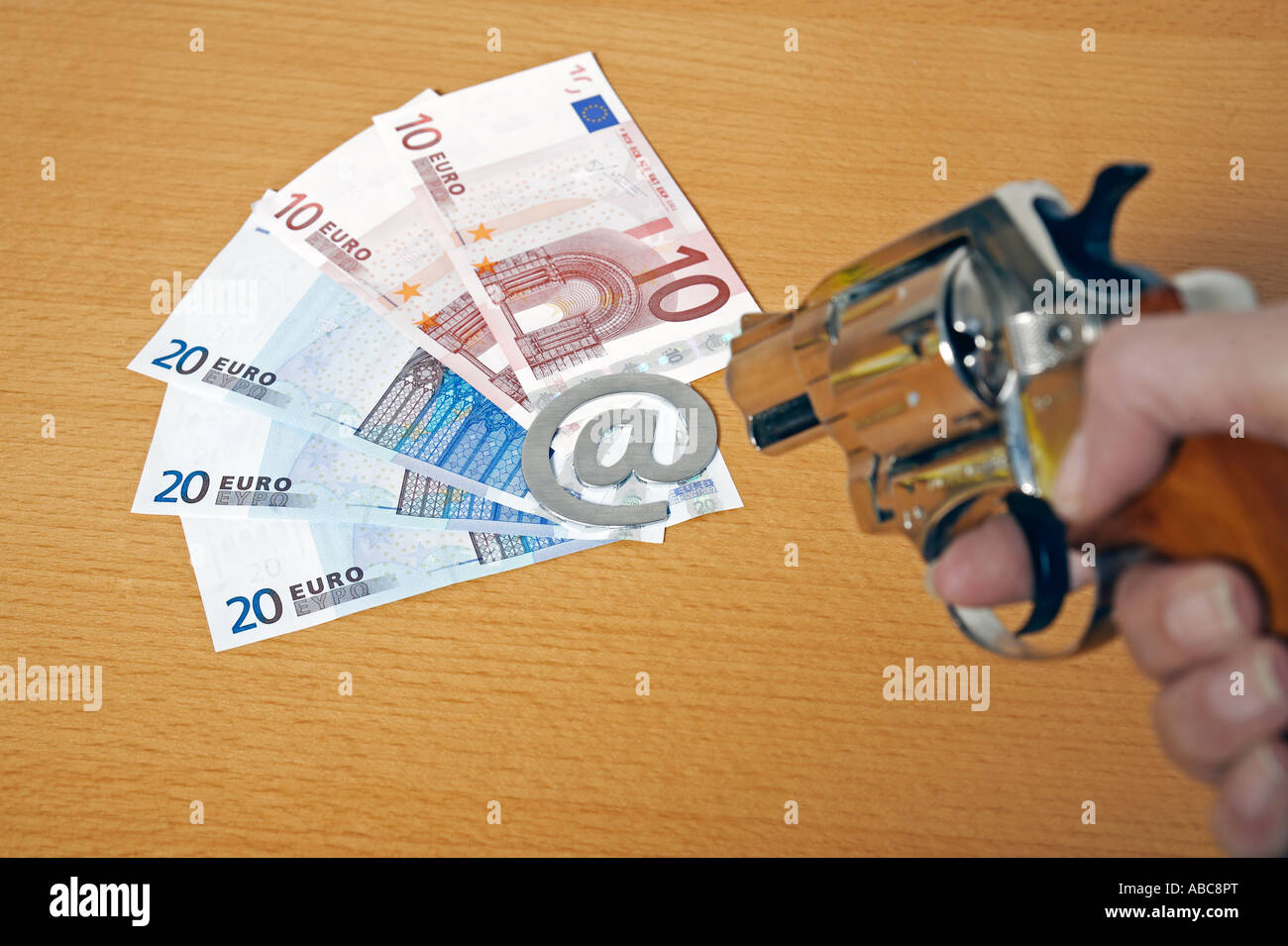 gun pointing euro bills with the arobase e mail sign on a table Stock ...