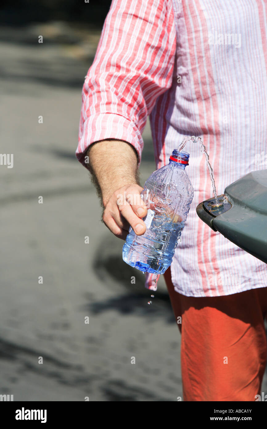 hand filling up water in a plastic bottle at a public spring fresh ...