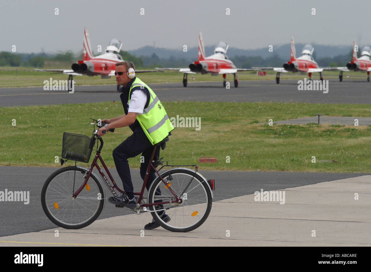 Airport groundcrew on bicycle waiting to cross ramp apron taxiway with ...