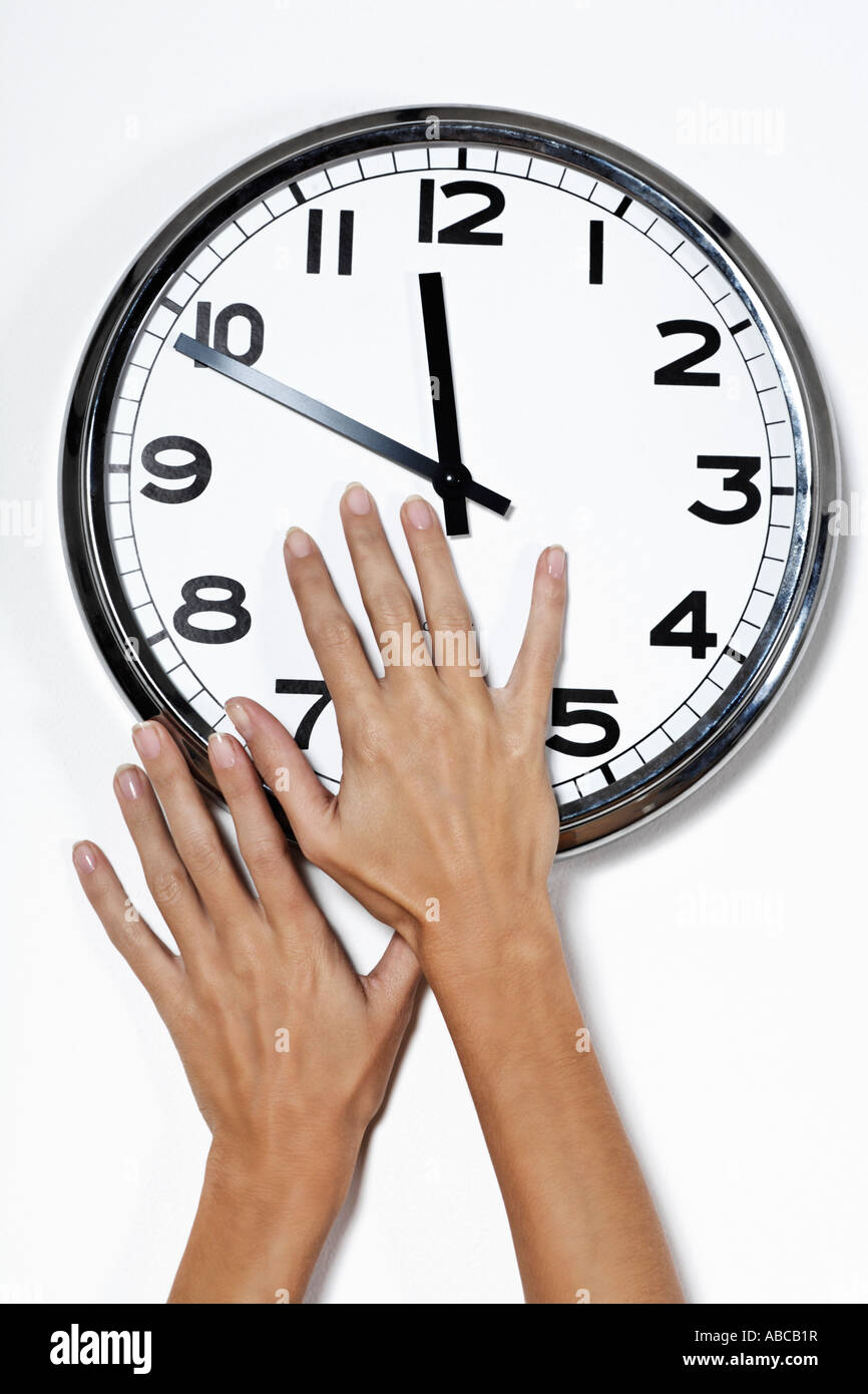 hands trying to stop the advance of the time by grabbing needle of a ...