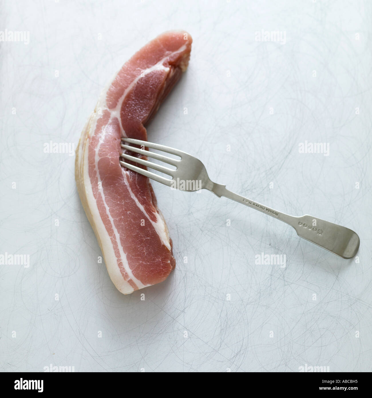 Rashers of streaky bacon on fork and metal worktop Stock Photo - Alamy