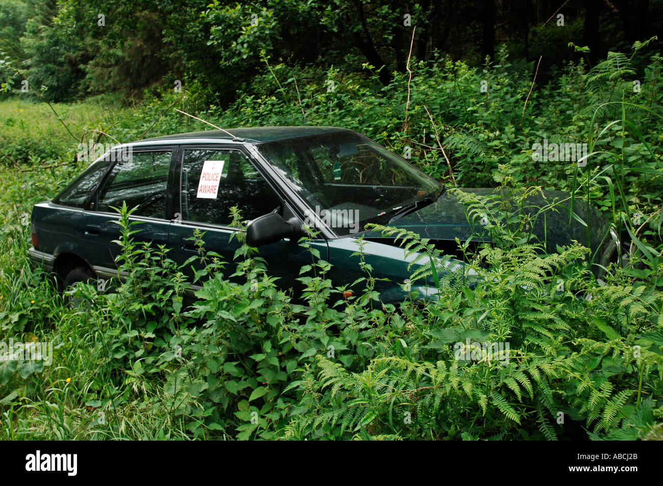 Abandoned car in undergrowth with police aware sign Stock Photo - Alamy