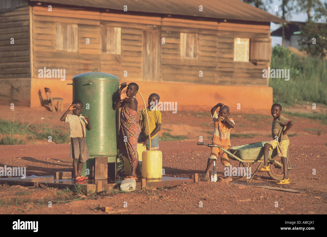 Children collecting water from stand pump in small rainforest town in ...